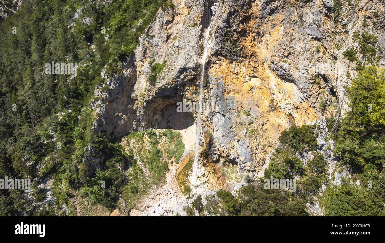 Majestic rinka waterfall flows down rocky cliffs into the lush green ...