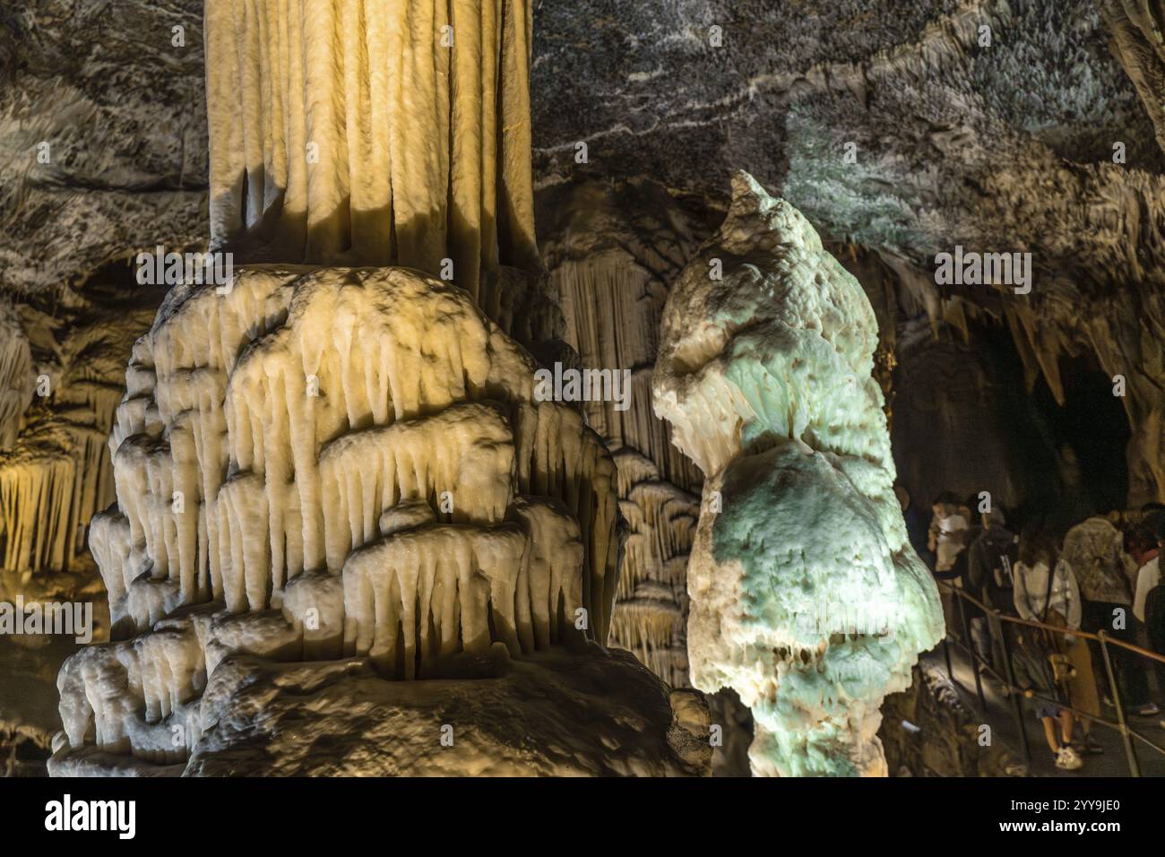 Tourists marveling at illuminated stalactites and stalagmites ...