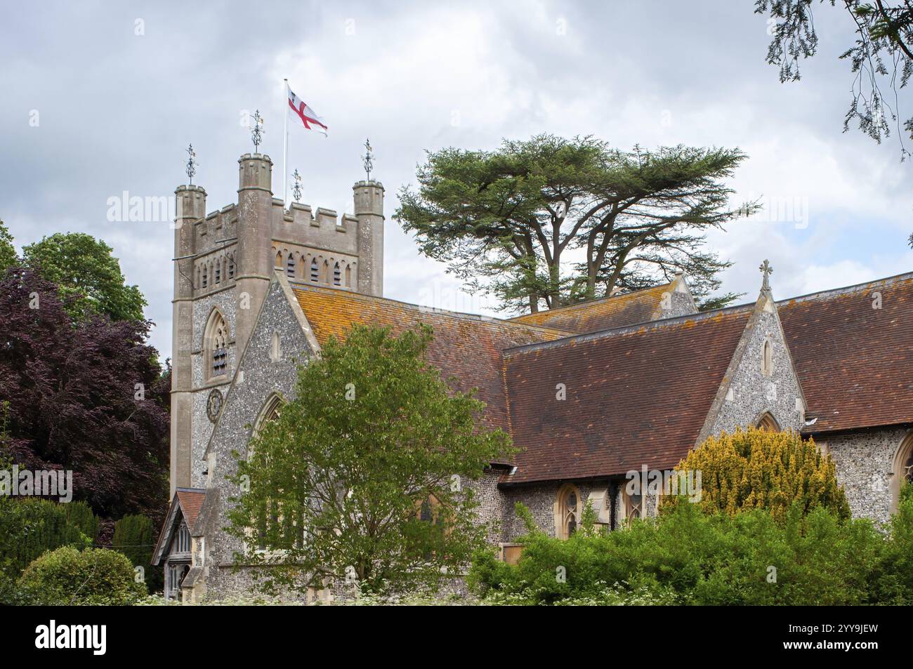 English church waving the flag of england from its tower in a cloudy ...