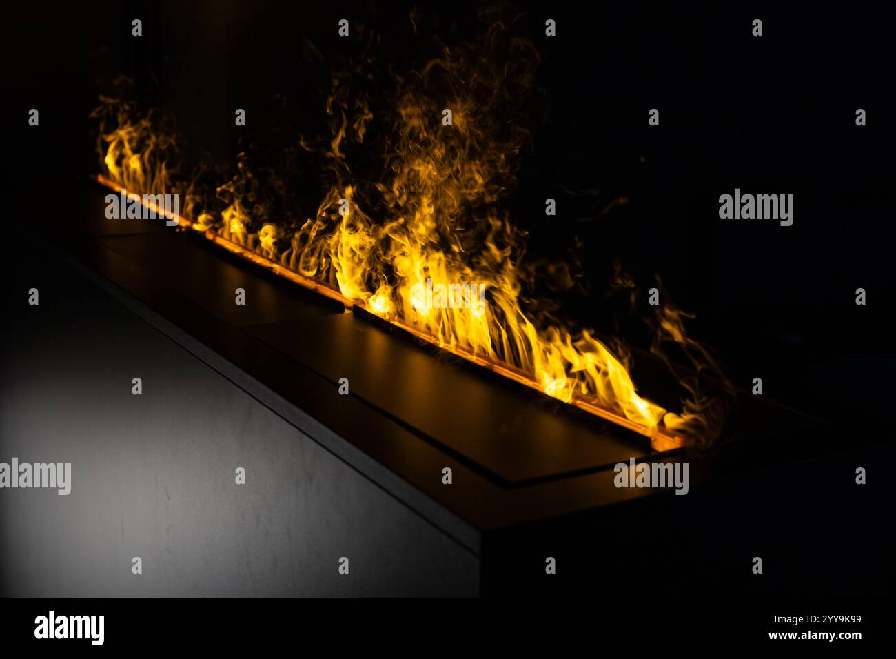 Dramatic close-up of a modern linear ethanol fireplace with bright ...