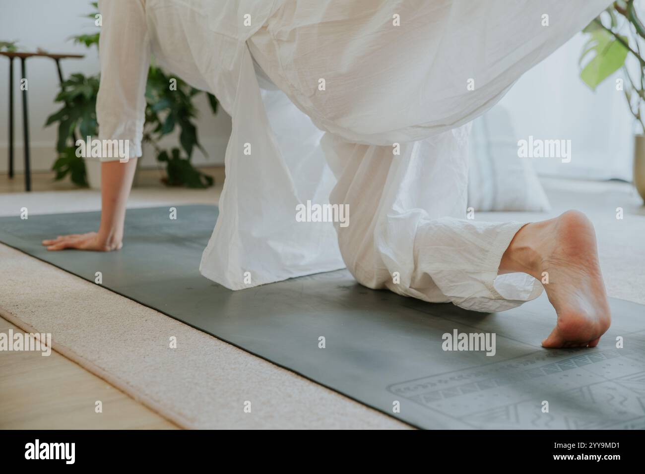 a woman wearing white clothes doing balancing table pose, yoga at home ...