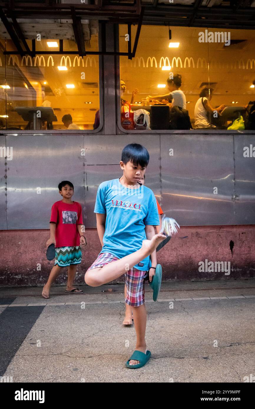 Filipino boys kick a shuttlecock between each other on the streets of China Town, Manila ...