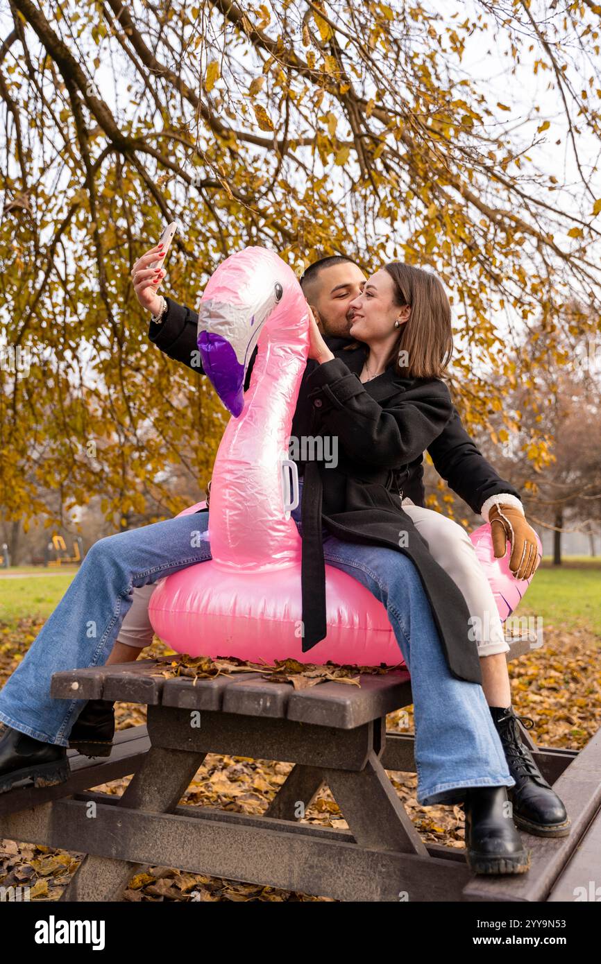 portrait of two young lovers taking a selfie having fun riding an ...