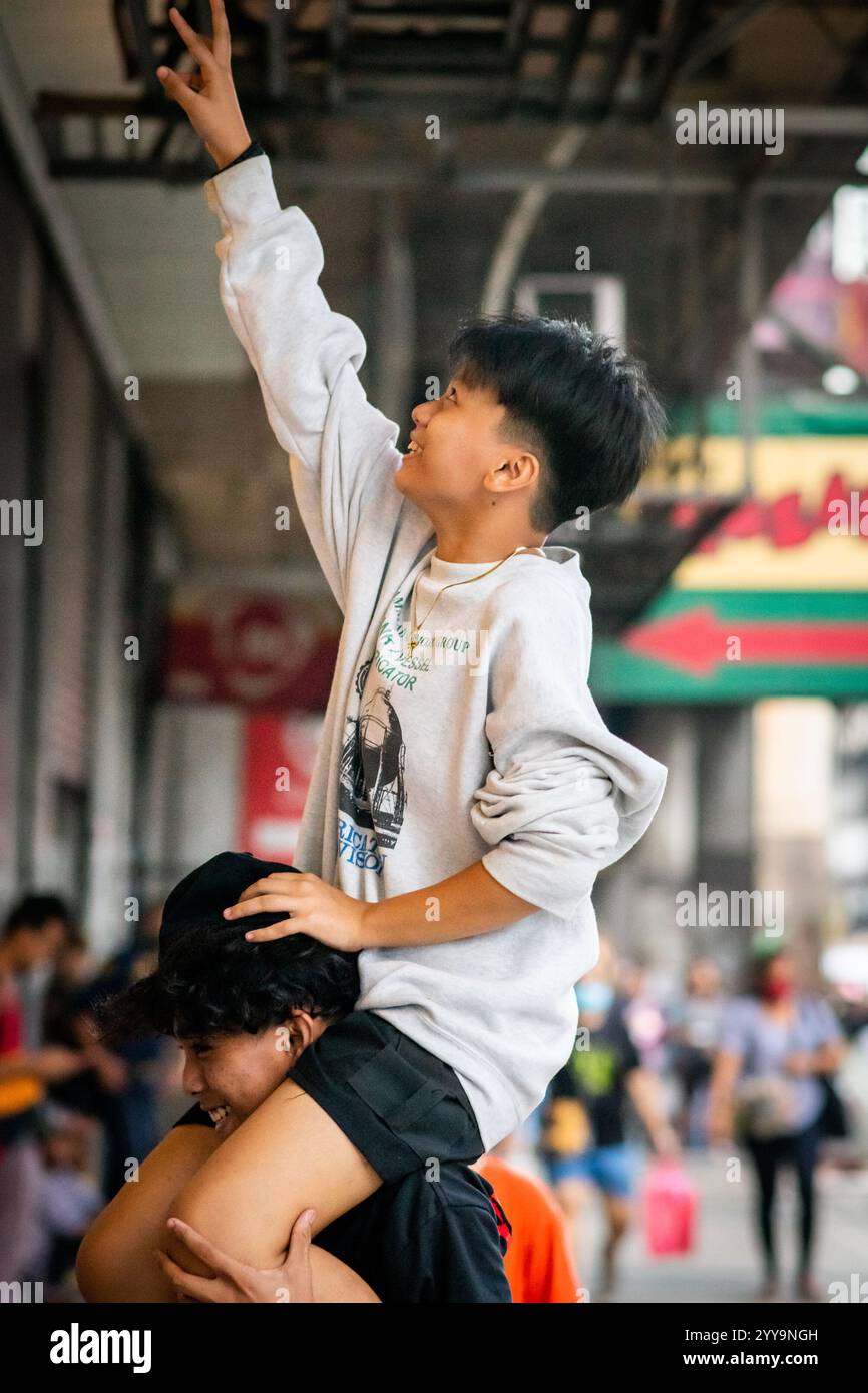 Filipino boys struggle to get their ball down from a high wall. They ...
