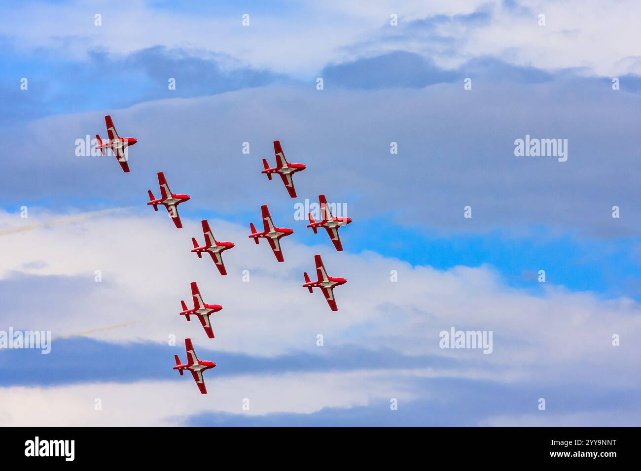 A group of red airplanes fly in formation in the sky. The formation is ...