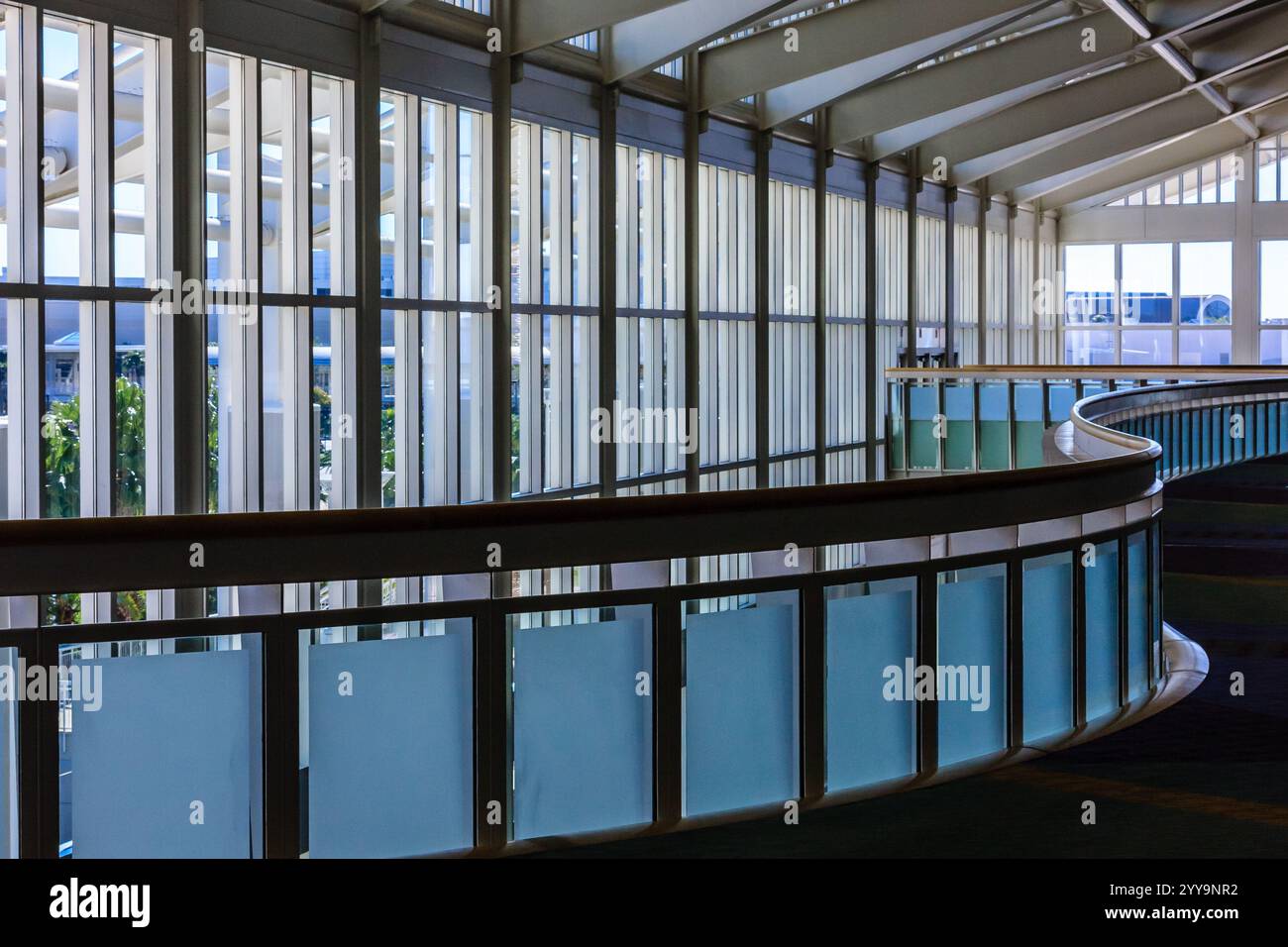 A long hallway with blue glass windows and a blue railing. The blue ...