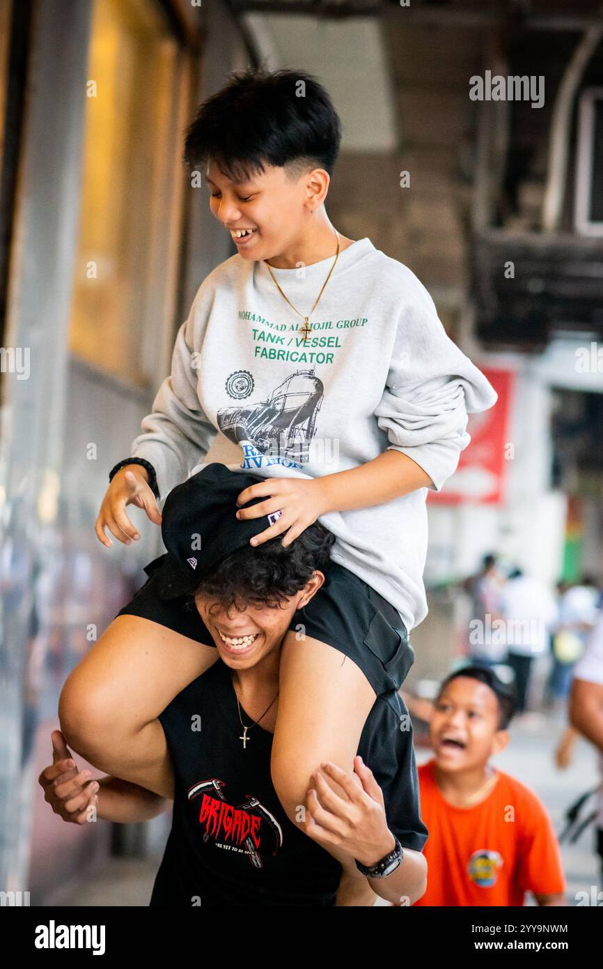 Filipino boys struggle to get their ball down from a high wall. They are playing on the streets ...