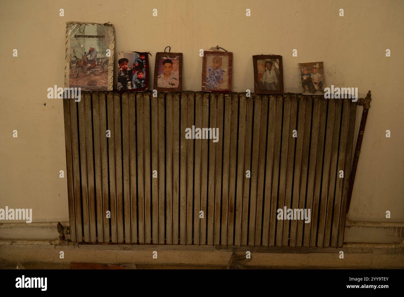 Photos of children and youths sit on a radiator in a hallway in the ...