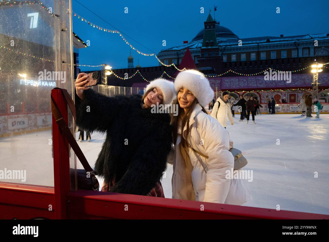 Two young women take a selfie at an ice rink installed at the Red ...