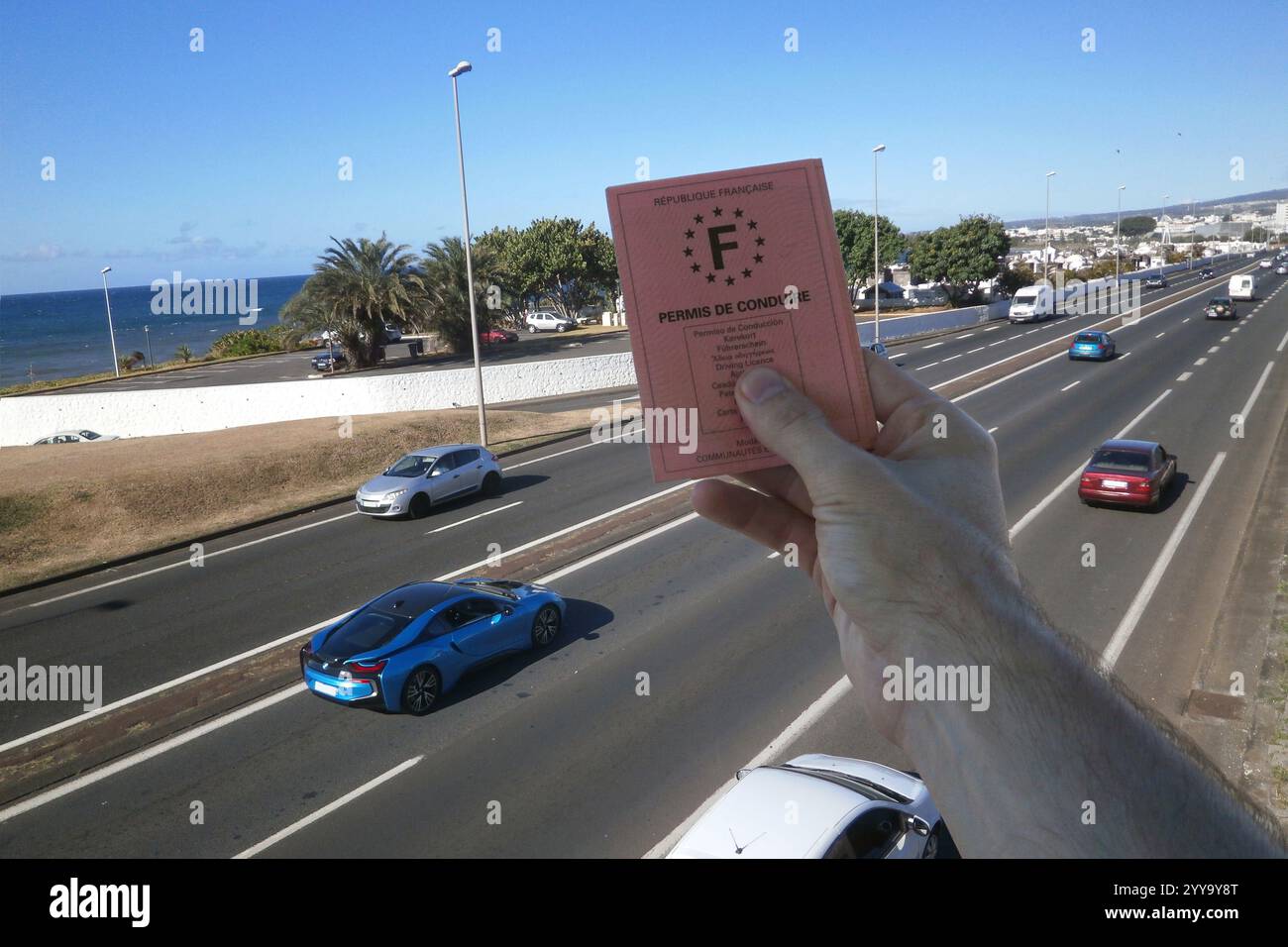 Right hand holding a French driver's license with the cars driving on a ...