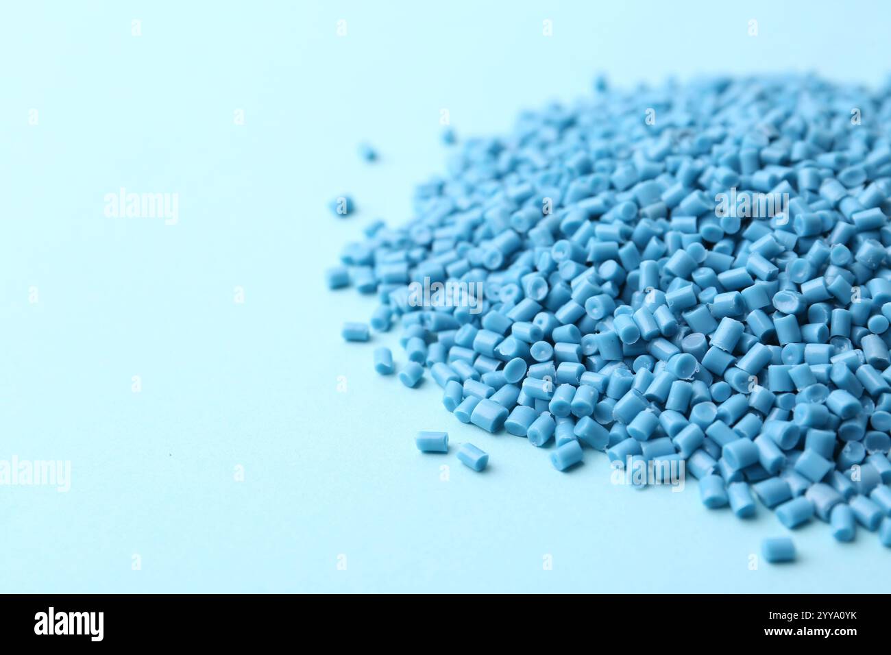 Pile of plastic granules on light blue background, closeup. Space for ...