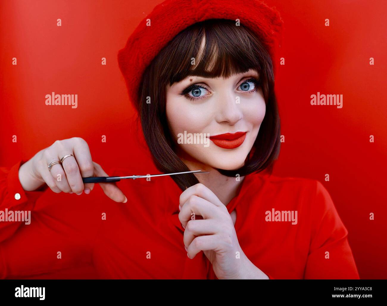 Haircut. Portrait of young woman hairdresser cutting hair with scissors ...