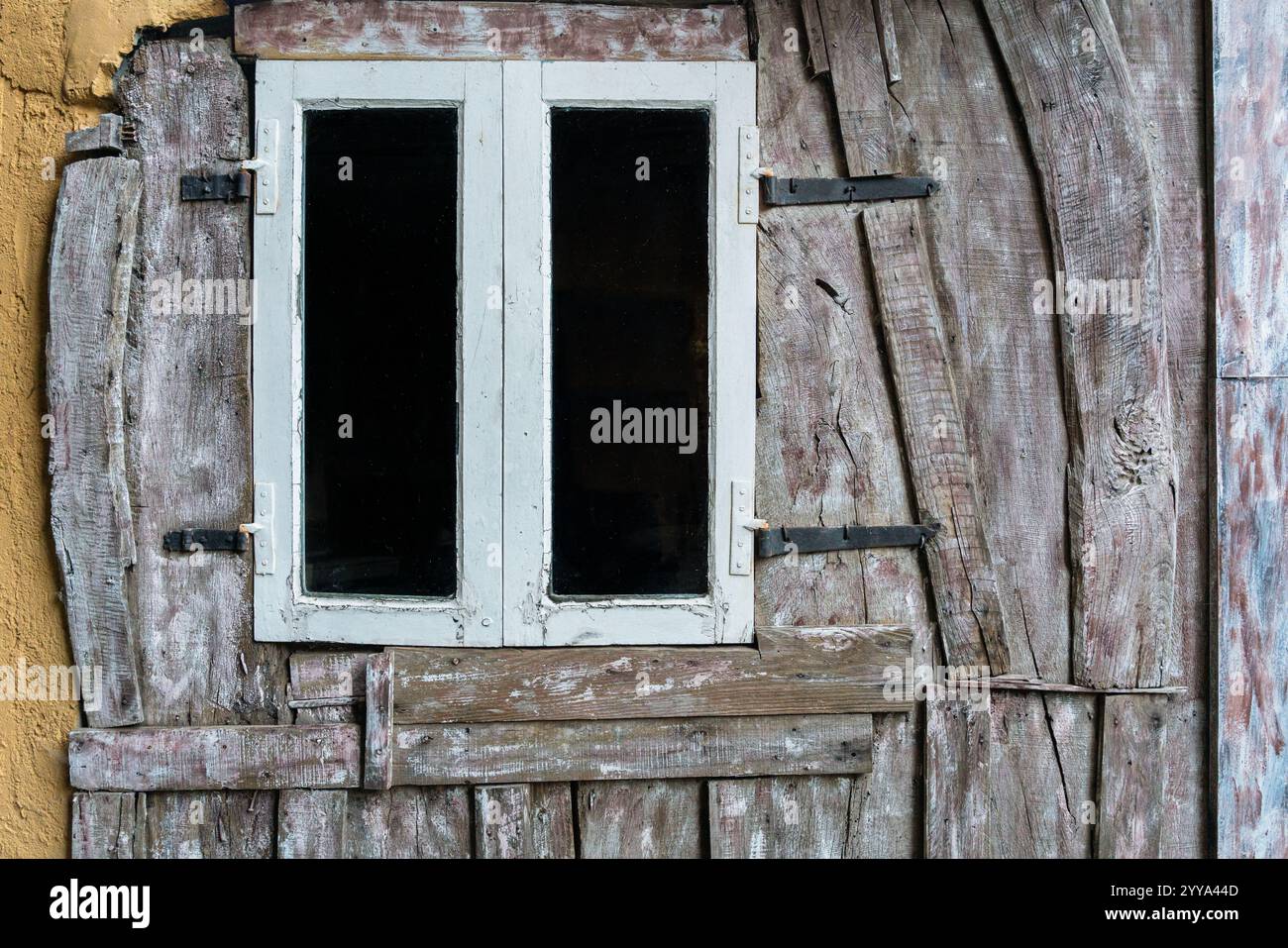 White window in the facade of an old wooden hut. The window is closed ...
