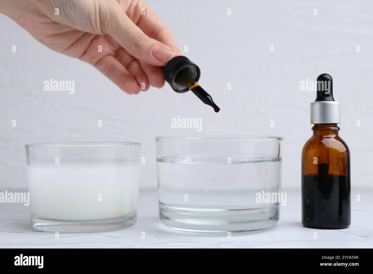 Iodine starch test. Woman dripping iodine into glass of water at white ...