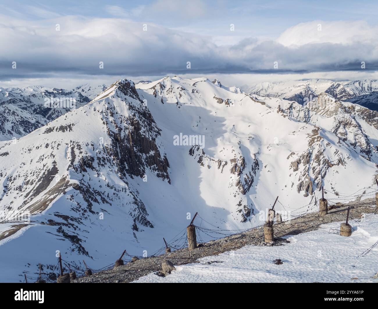 A rugged snowy mountain slope featuring remnants of a barbed wire fence ...