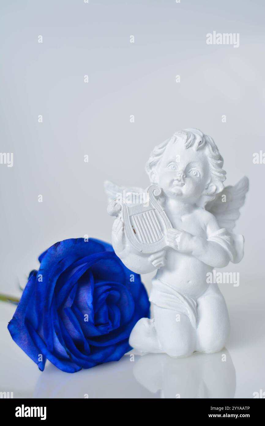 Cherub statue with blue rose on white background Stock Photo - Alamy