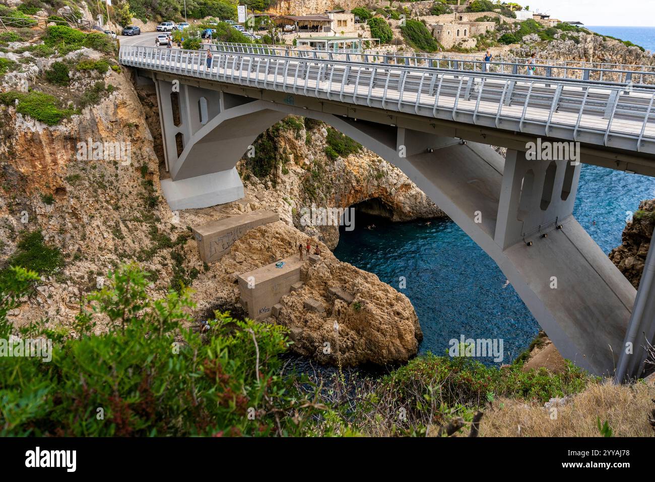 Scenic inlet called Ciolo with bathers and a concrete bridge, in the ...