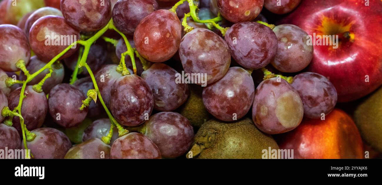 A vibrant display showcases ripe grapes, apples, and pears ...