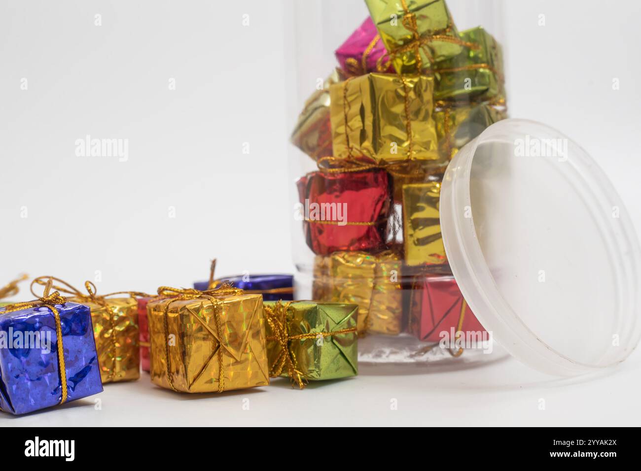 Colorful miniature gift boxes placed inside a clear plastic jar, lying ...