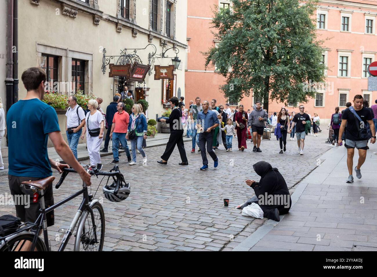 Warsaw, Poland - August 2024: A homeless woman dressed in black sits on ...