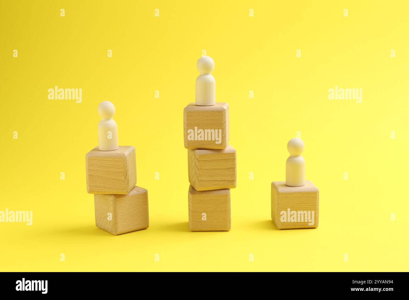 Human figures on stacked wooden cubes against yellow background ...