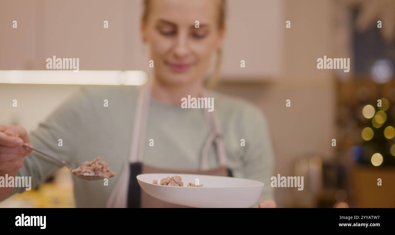 Woman puts meat into meat grinder and prepares holiday dishes Stock ...