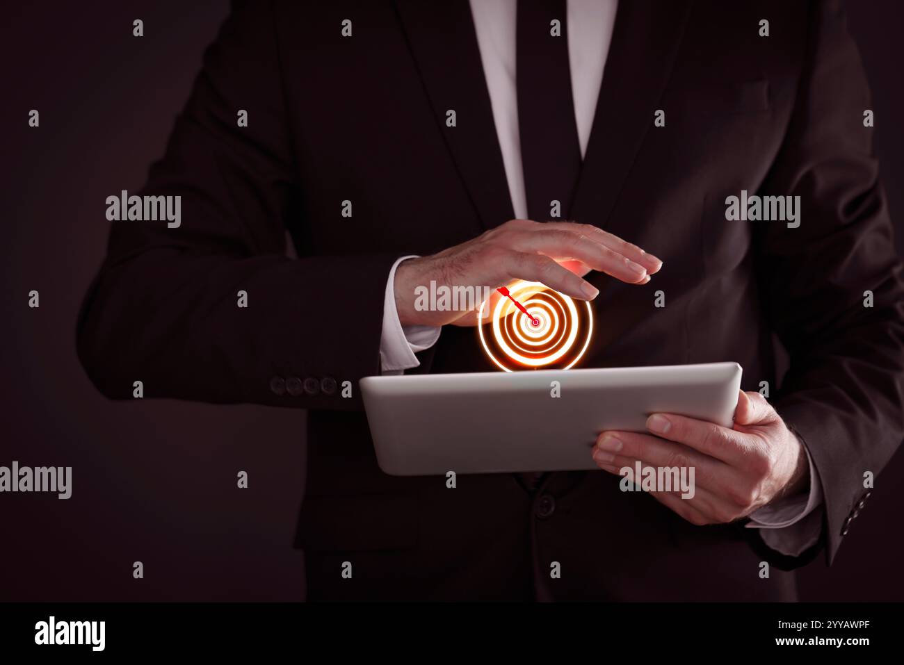 Businessman holding tablet and virtual target with arrow on dark ...