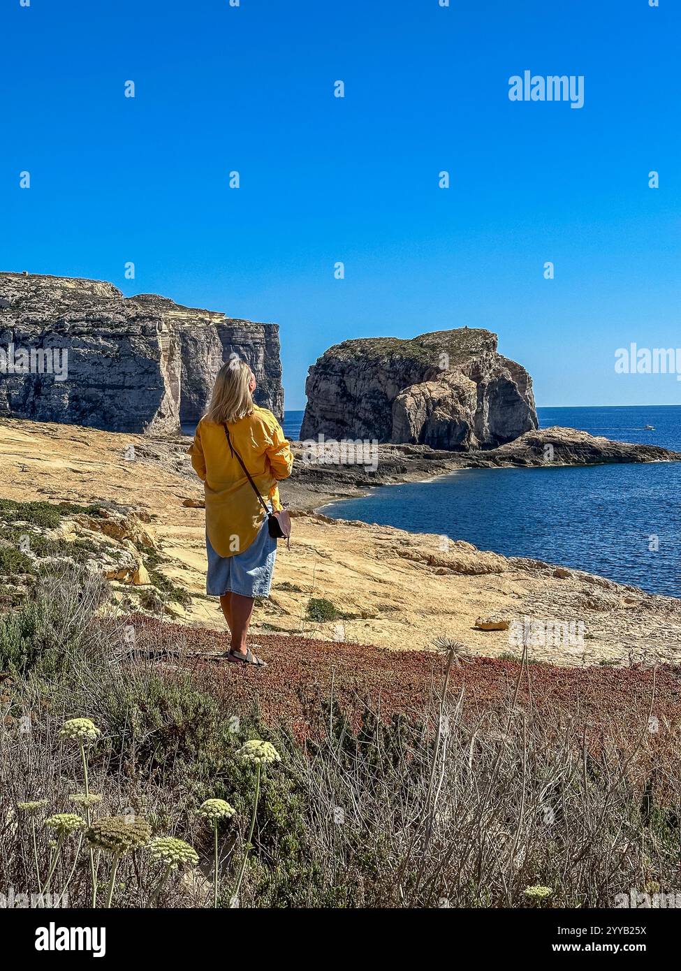 Woman stand and look at Dwejra Bay, Tilt Rock and Fungus Rock at Gozo ...