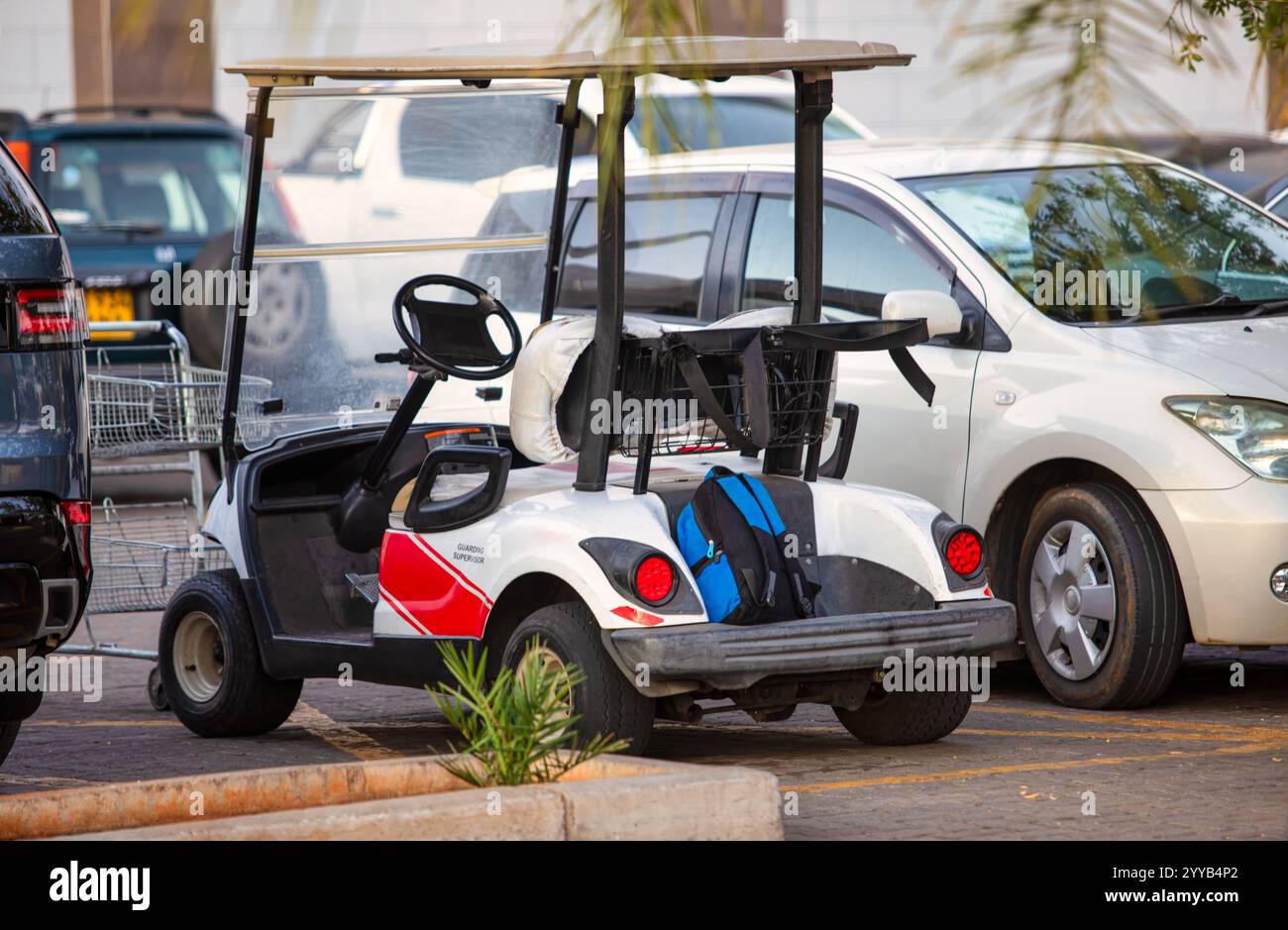 parking supermarket, golf cart security parked and waiting between the cars, modern african mall ...