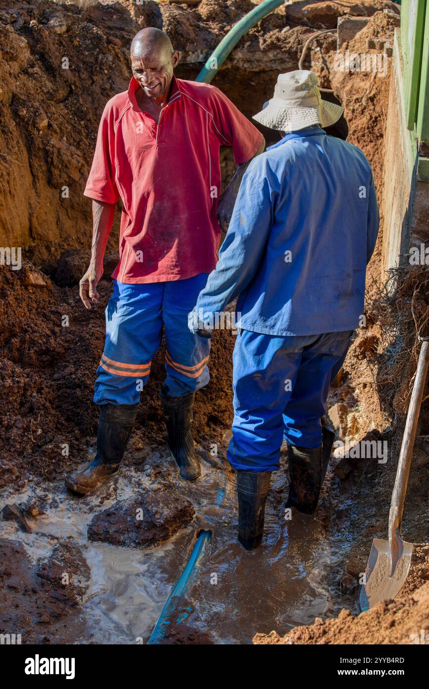 african american plumber construction workers fixing a blocked drainage ...