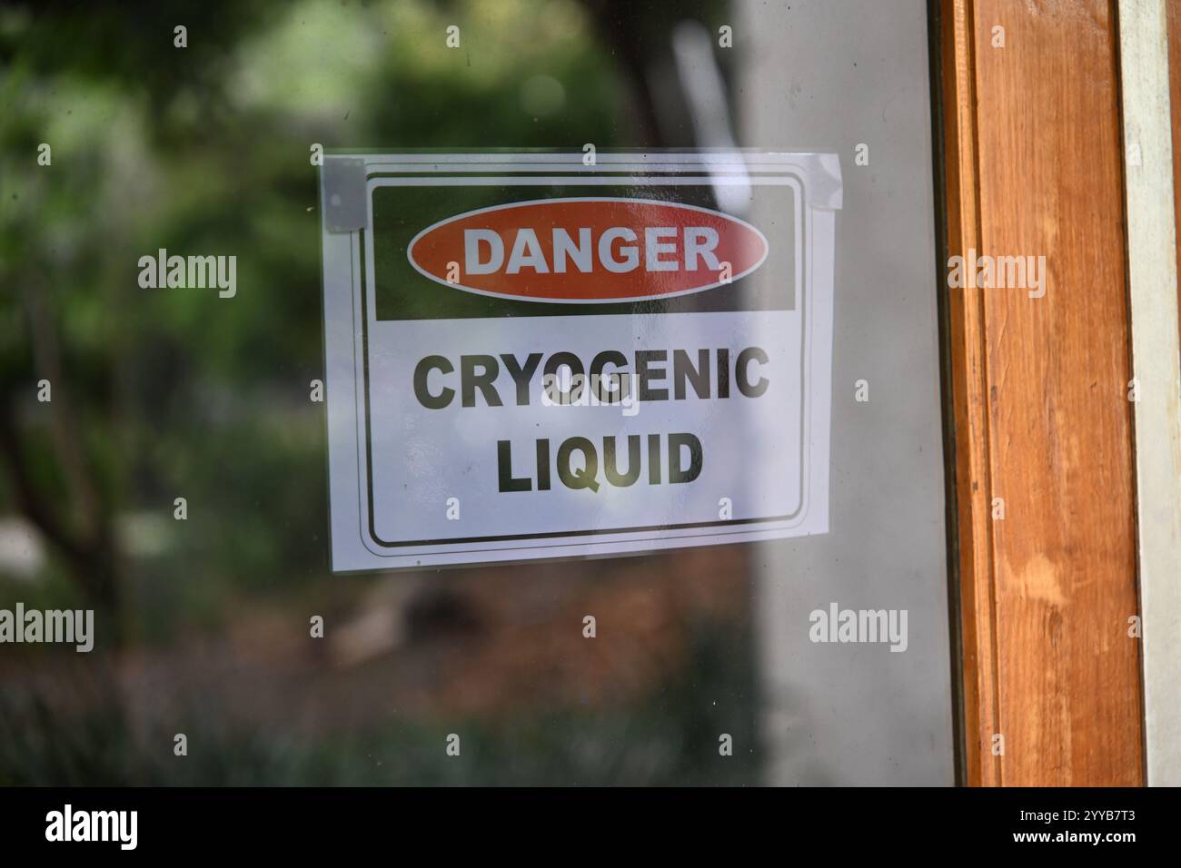 Small black, white, and red danger cryogenic liquid sign, behind glass ...