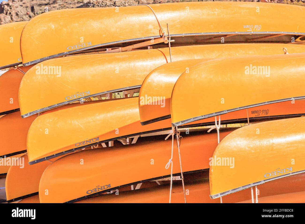 A row of yellow canoes are stacked on top of each other. The canoes are ...