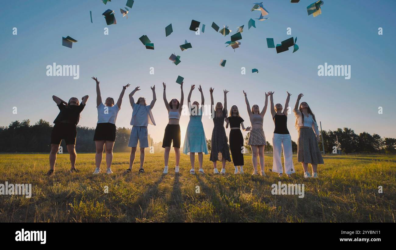 Happy students tossing books in the air to celebrate the end of the ...