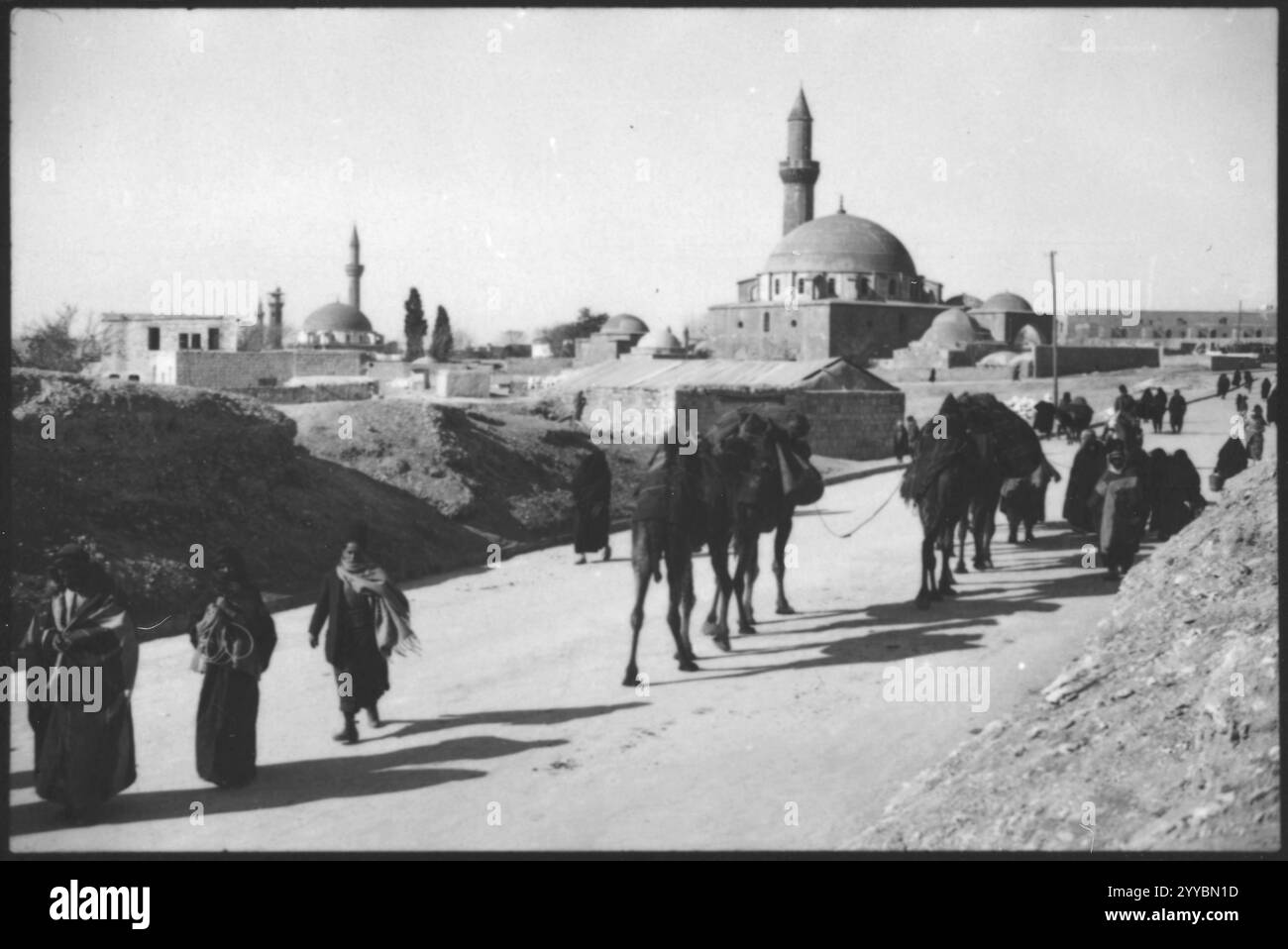 Syria, Aleppo: people with camels passing by on street, mosques in the ...