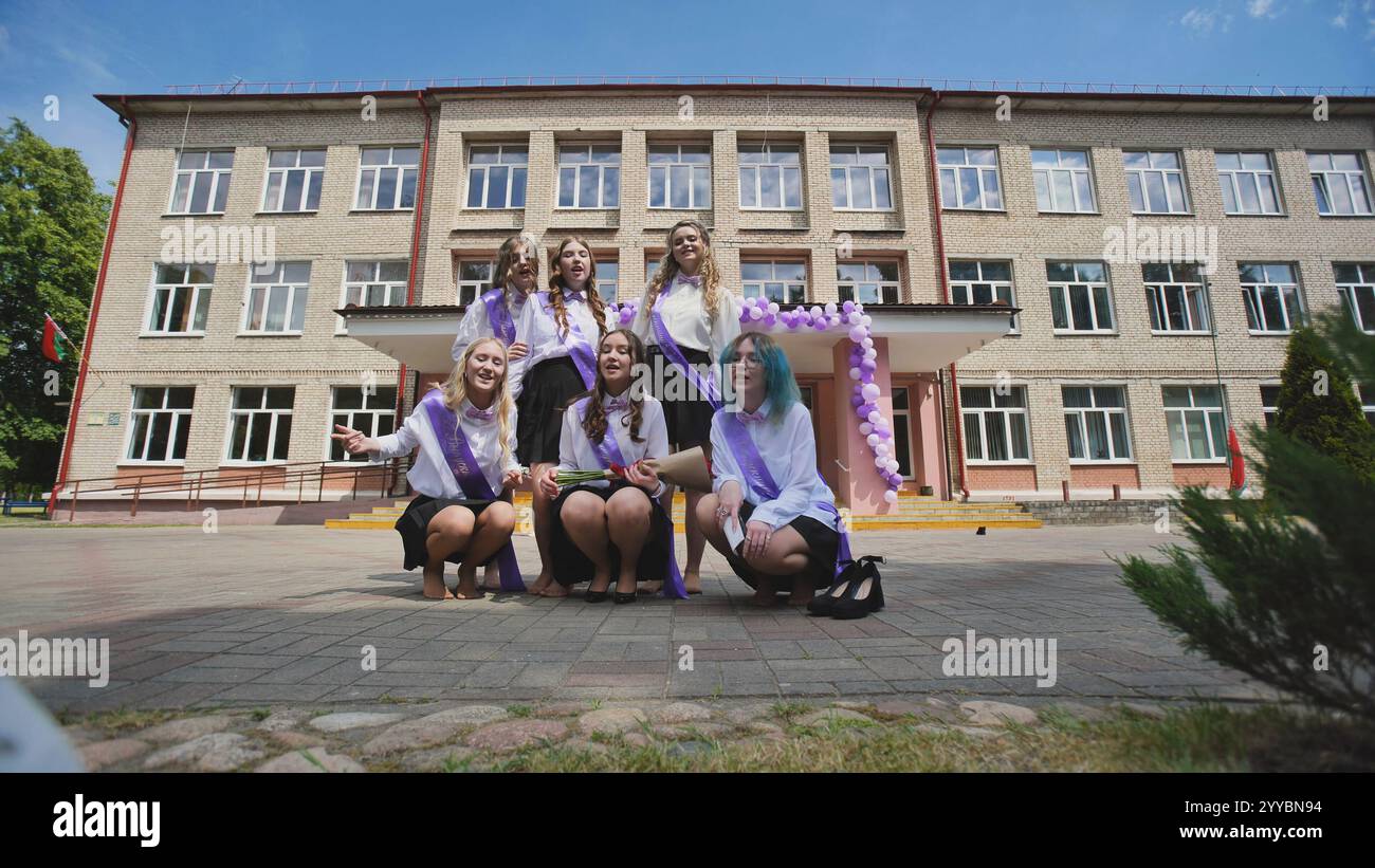 Cheerful female graduates gather for a photo in front of their high ...