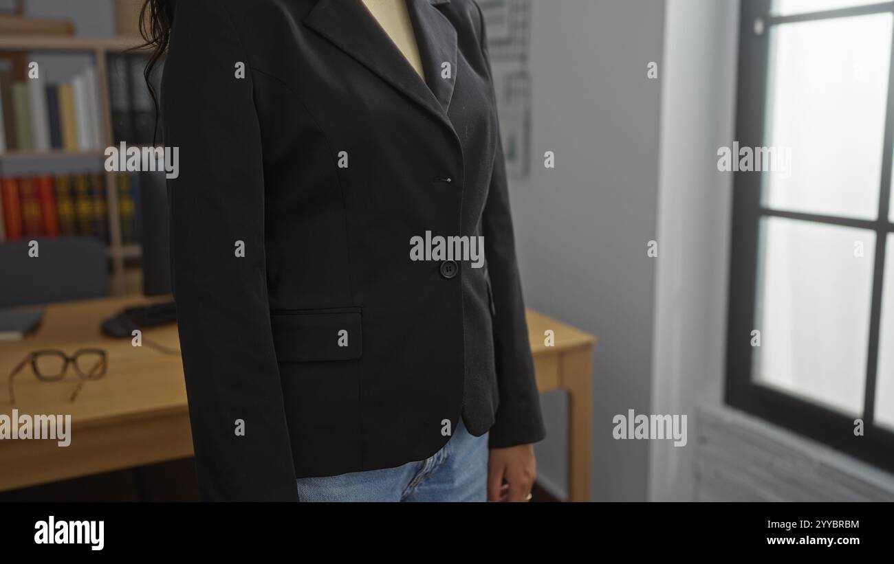 Woman standing in office room next to desk and bookshelves by window ...