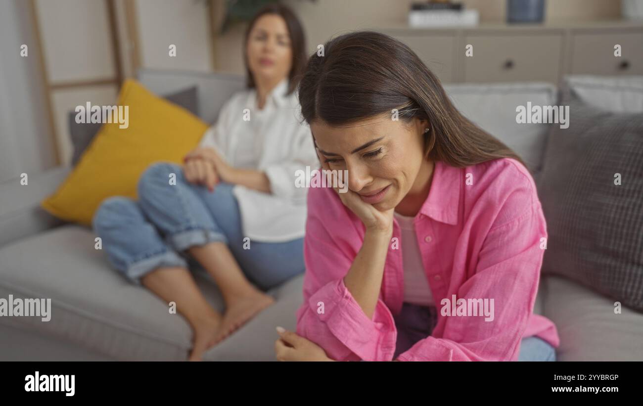 Woman crying sitting beside another woman on a couch in a living room ...