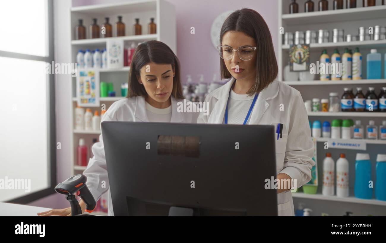 Two hispanic women pharmacists in white coats working together at a ...