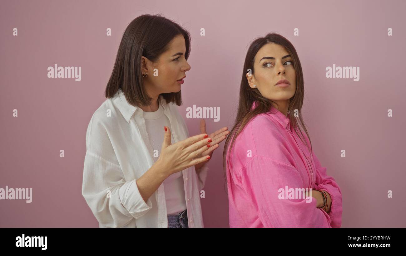 Two women having a serious conversation against an isolated pink ...
