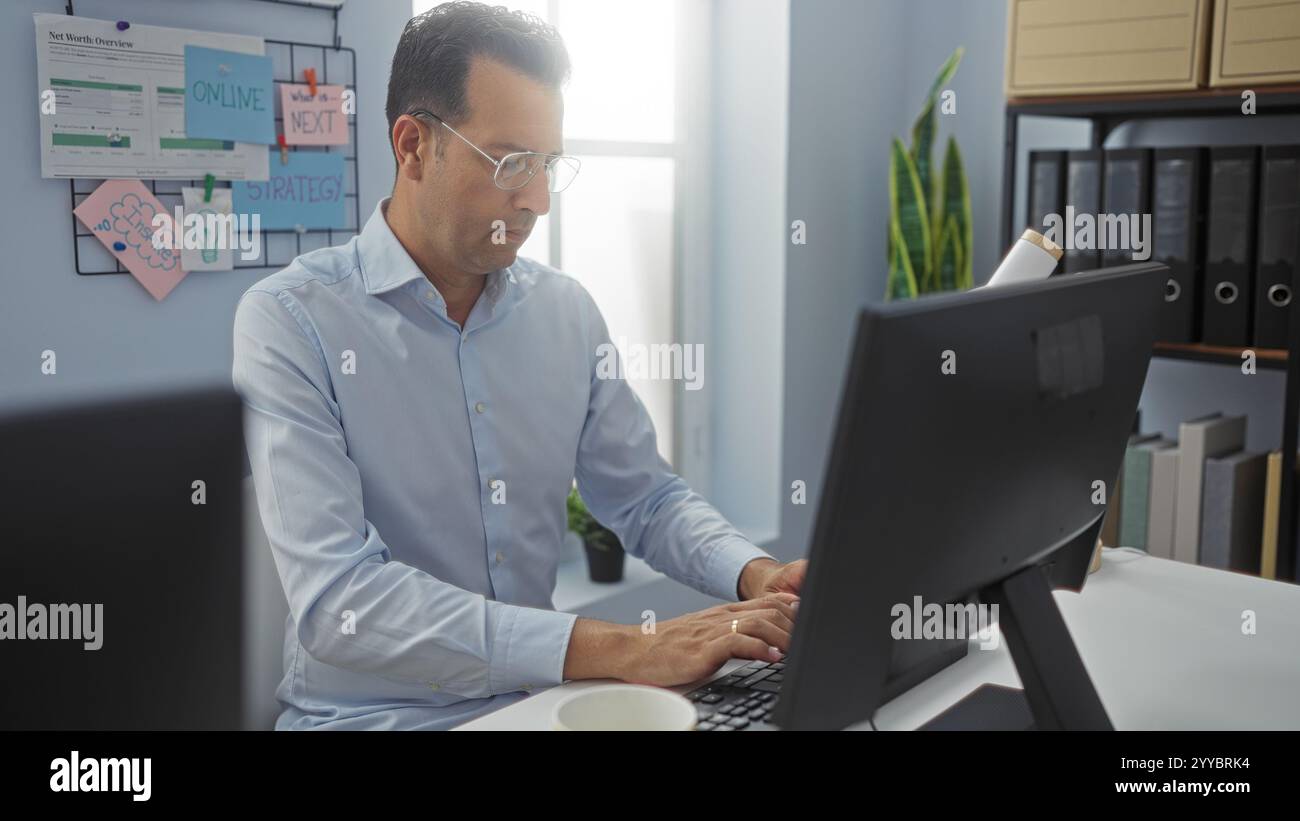 Hispanic man working diligently at his computer in a modern office ...