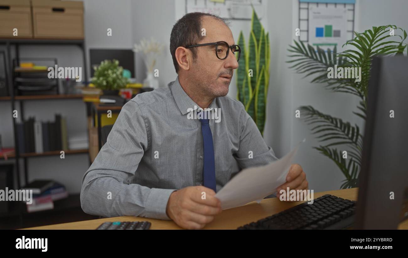 Middle-aged hispanic bald man working indoors in an office, holding ...