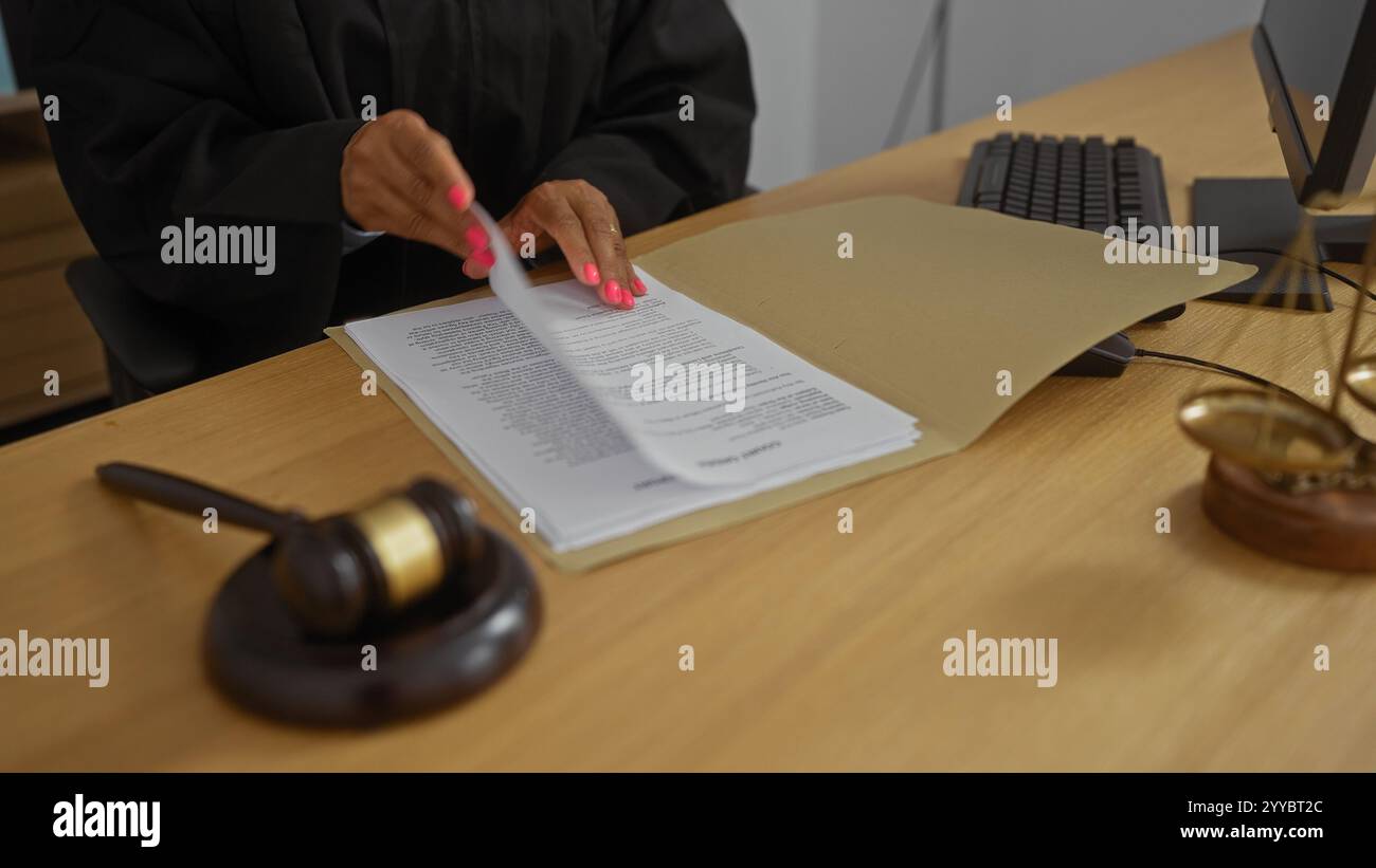 Woman judge reviewing legal documents with hands at desk in courtroom ...