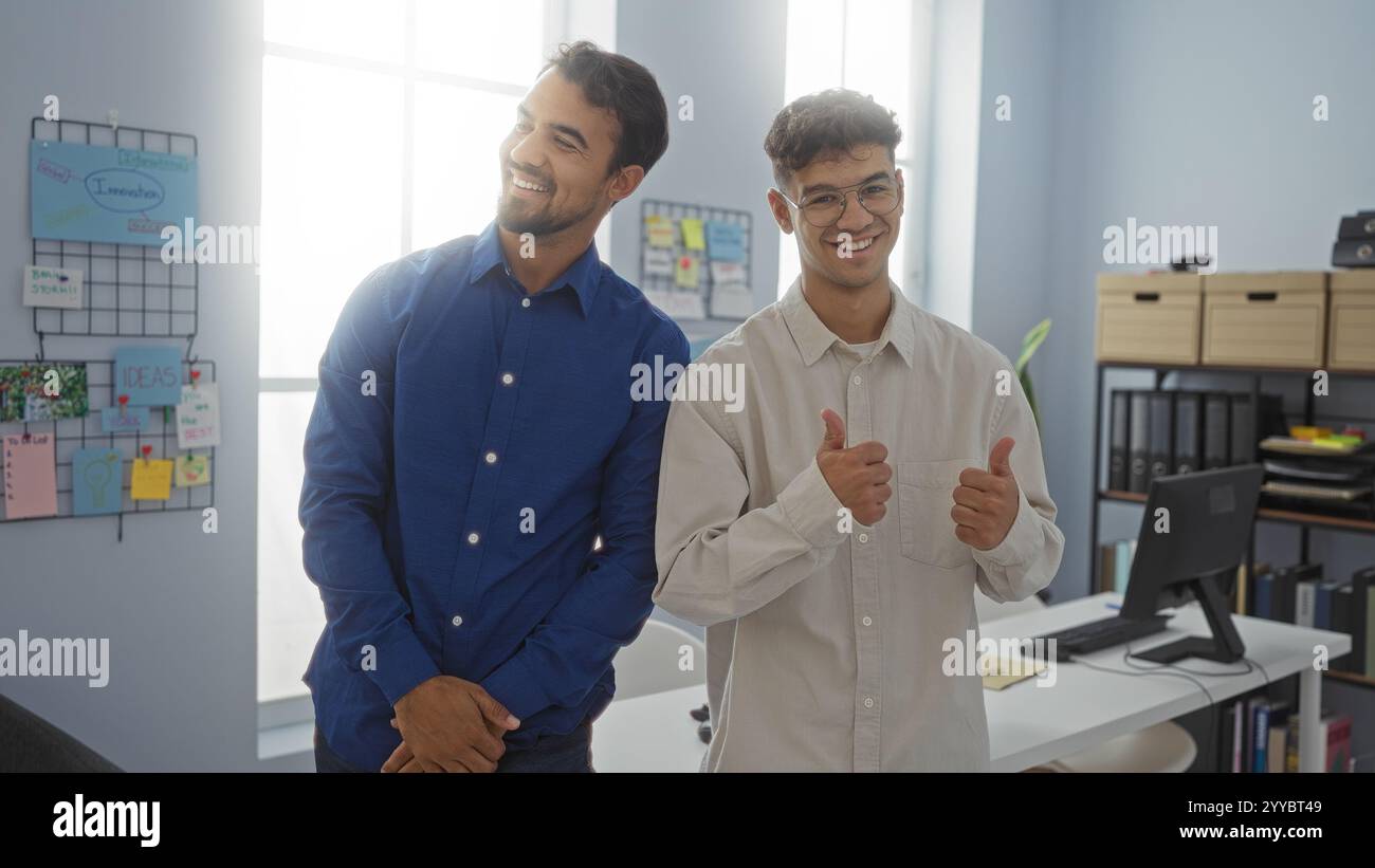 Two hispanic men standing together in an office, looking cheerful, one ...