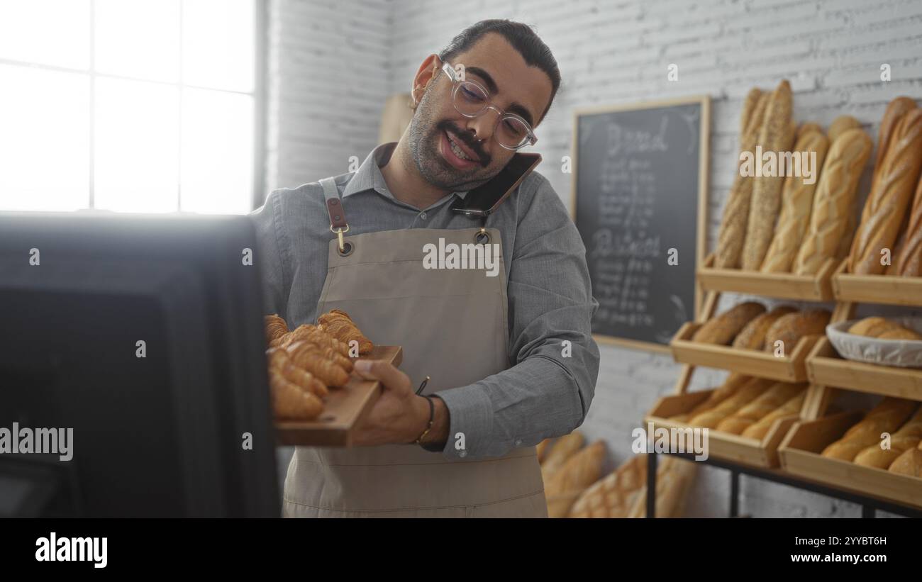 Young man with moustache working in a bakery, holding a tray of ...
