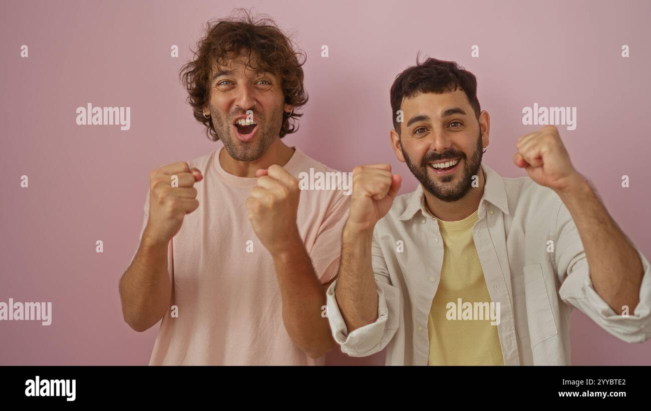 Two cheerful men celebrating together against a pink background ...