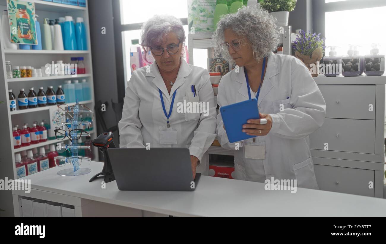 Two mature women pharmacists working together in a busy pharmacy ...