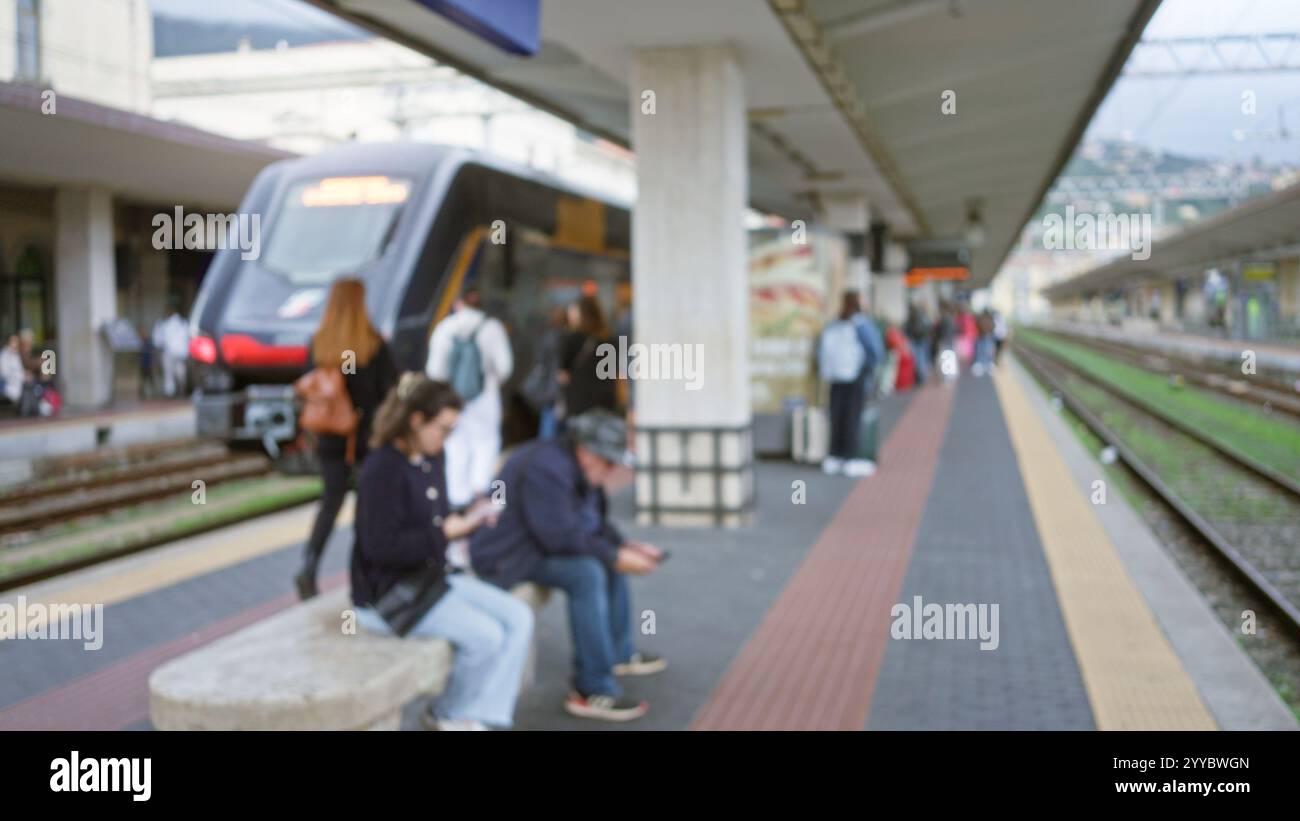 Blurred railway station scene with people waiting and train in ...