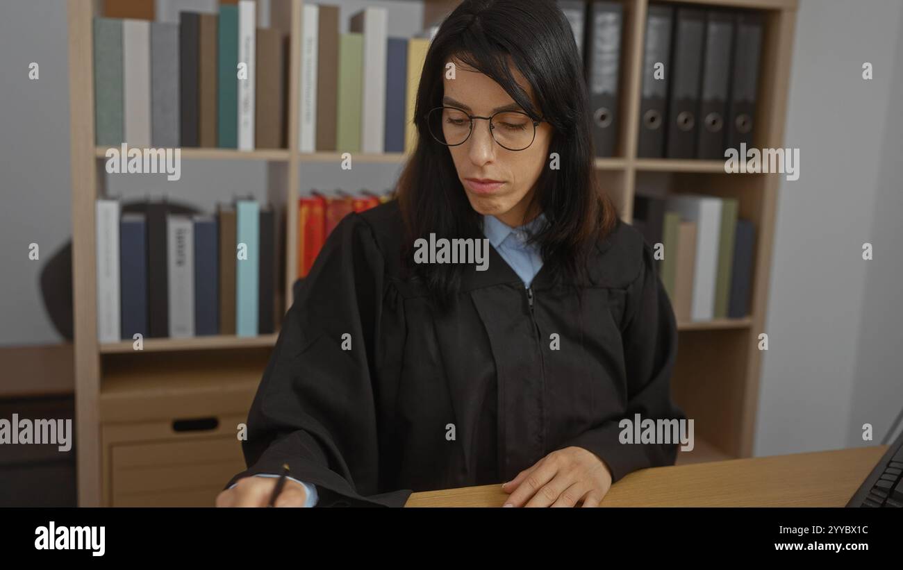 Woman judge in a black robe working in an office with shelves filled ...