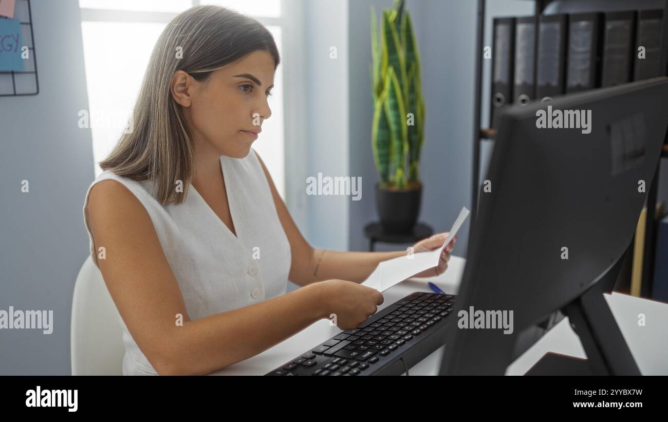Young woman working on computer at office desk in an indoor workplace ...