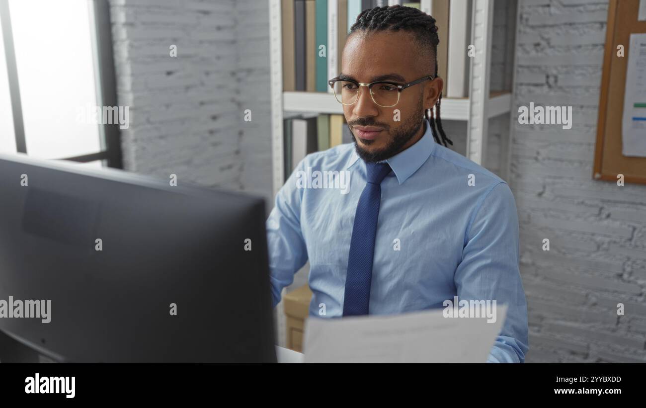 Young man with braids working in an office setting, focused on the ...
